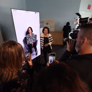 Alice Ginsburg stands next to her survivor story hologram screen